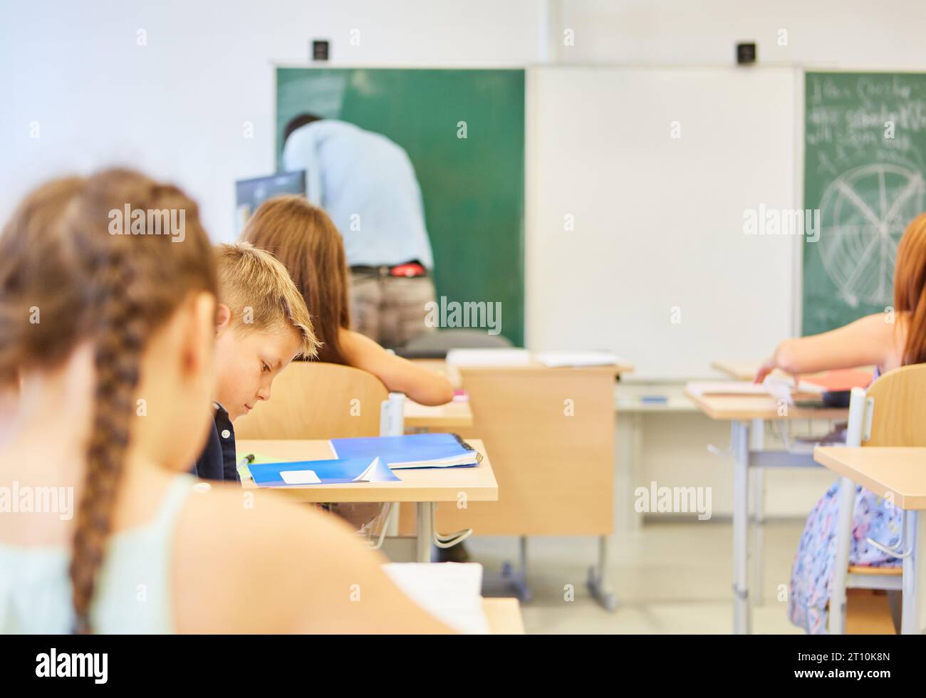 Male and female students sitting in classroom during lecture at school ...