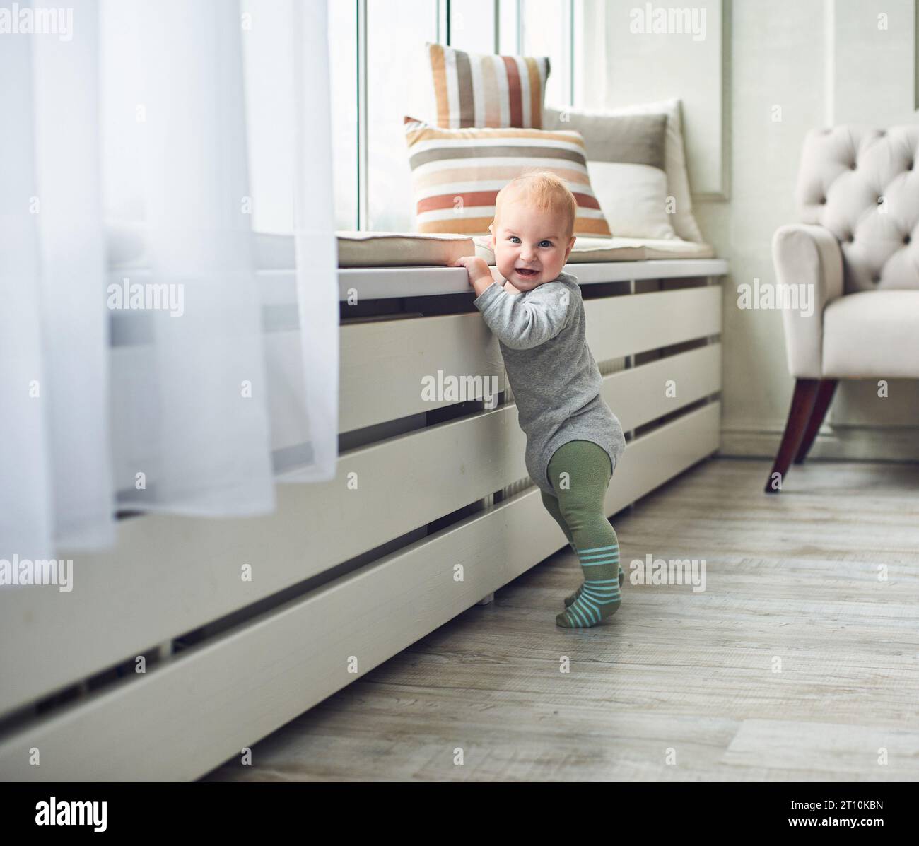 Little cute 8 months baby boy stands with support near window at home ...