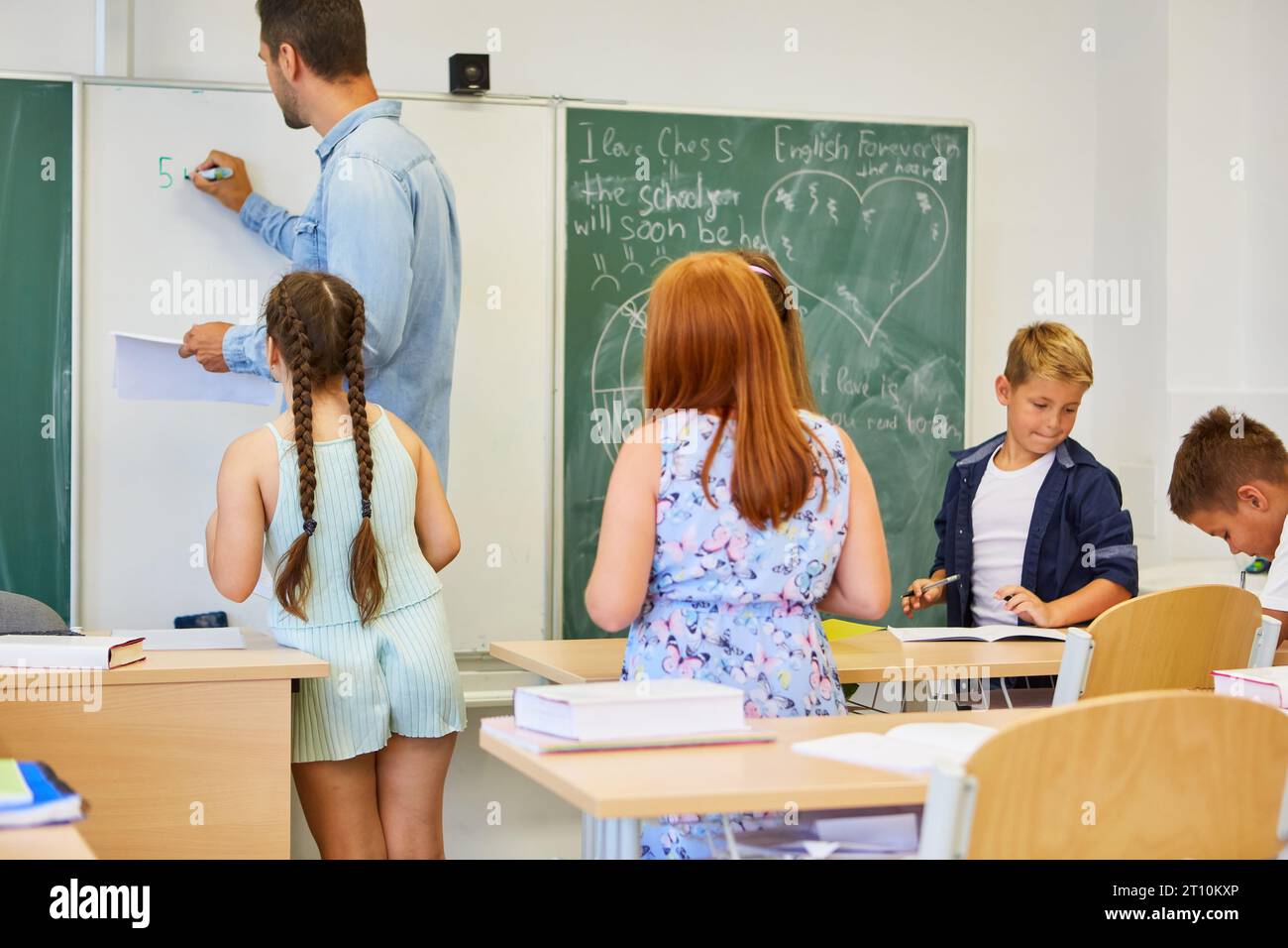 Male teacher teaching mathematics to elementary students in classroom ...