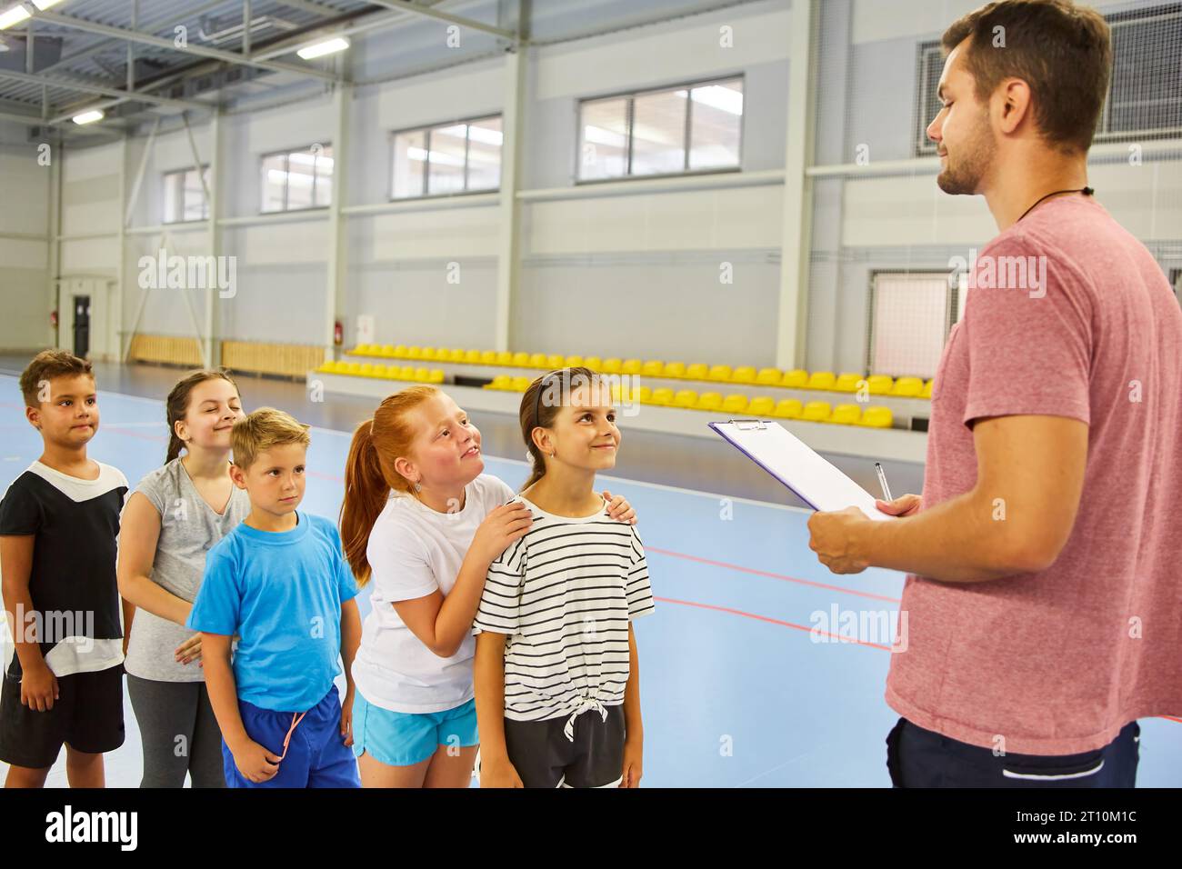 Male and female students giving physical test to teacher while standing ...