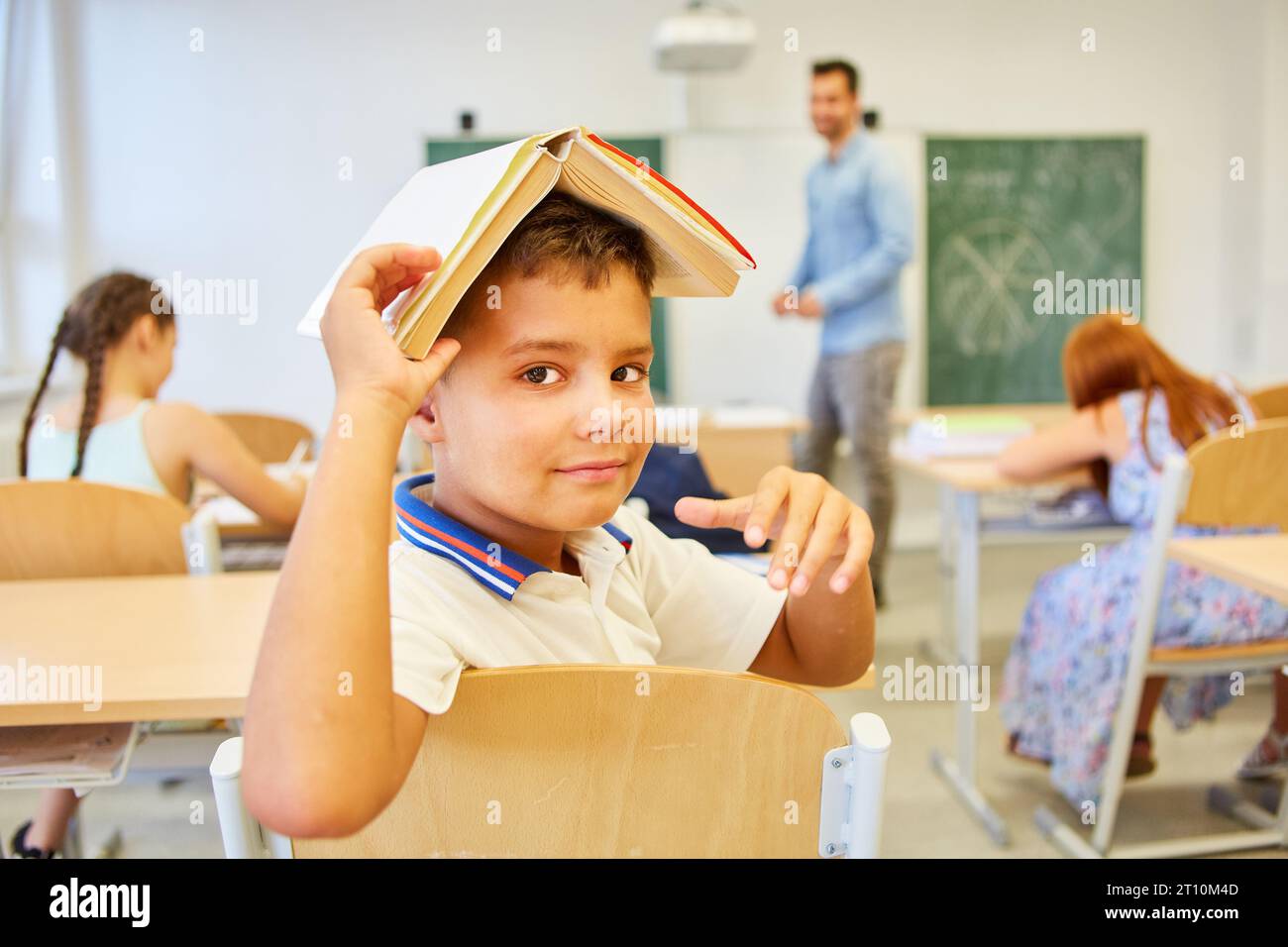 Portrait of male elementary schoolkid with book overhead sitting in ...