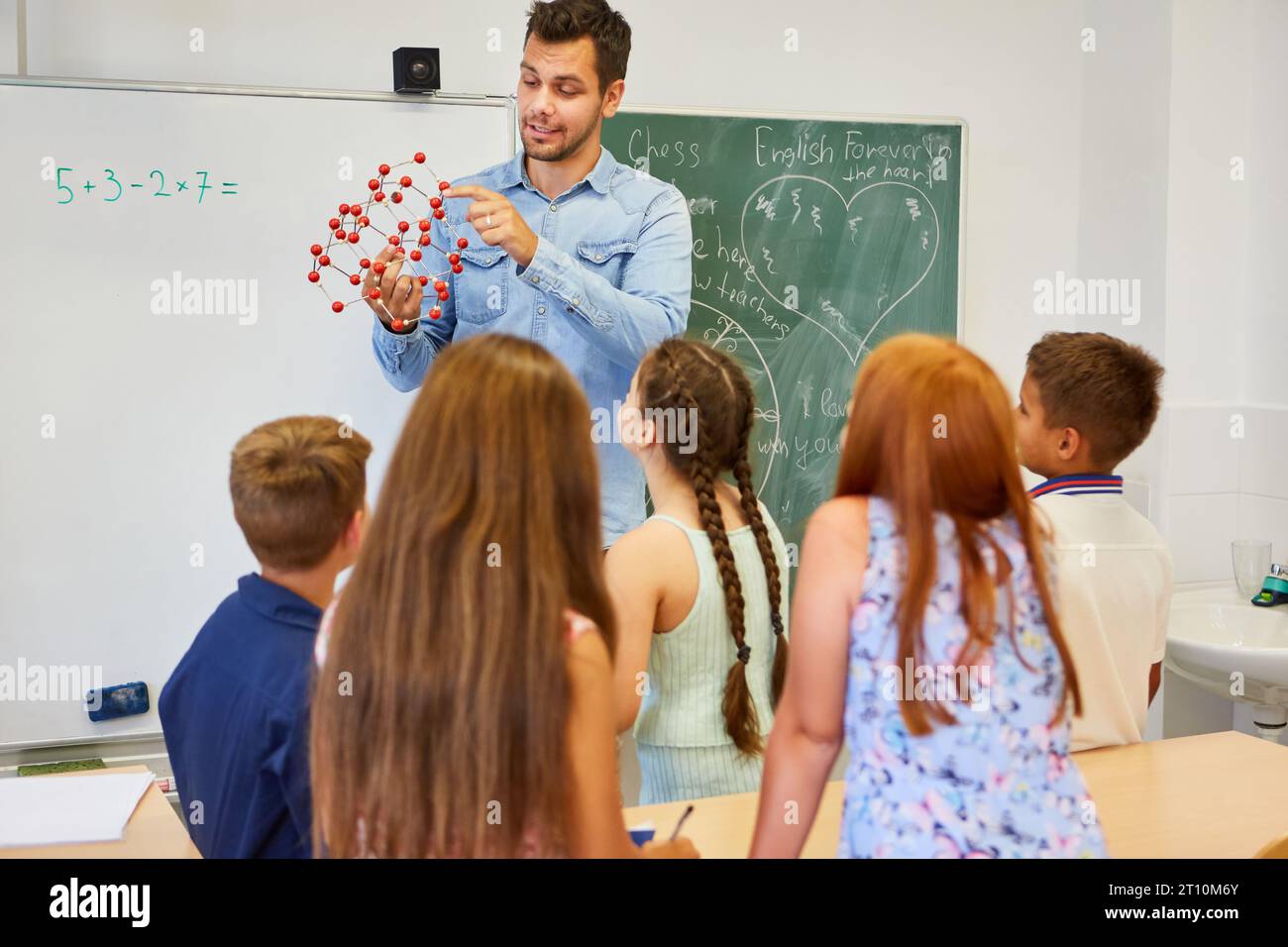 Male teacher explaining molecular structure to elementary students in ...