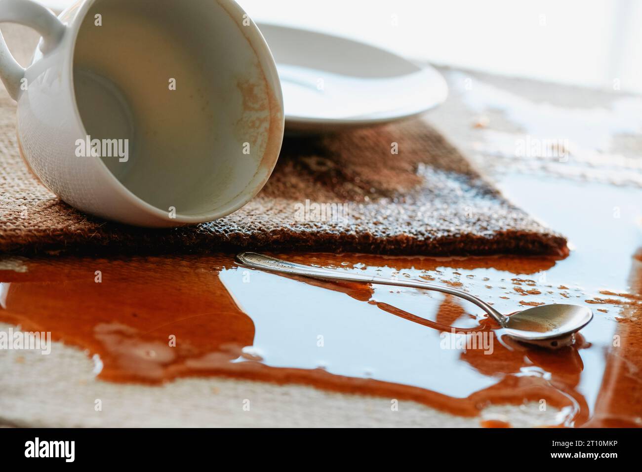 a cup of coffee spilled accidentally on the tablecloth that covers the ...