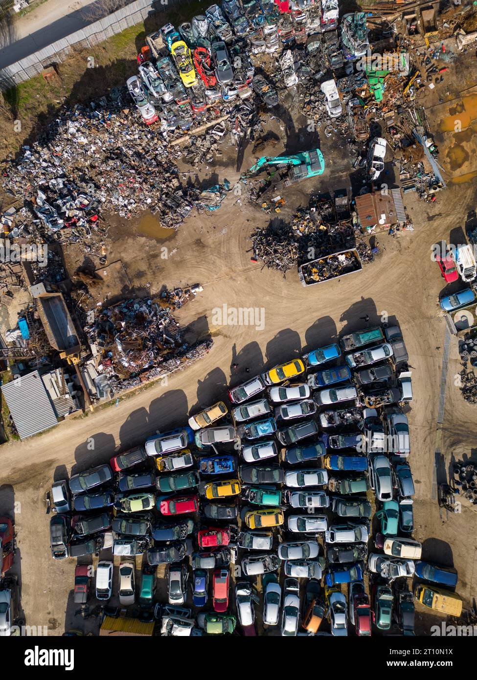 aerial view of a car dump, where a machine is seen separating old cars ...