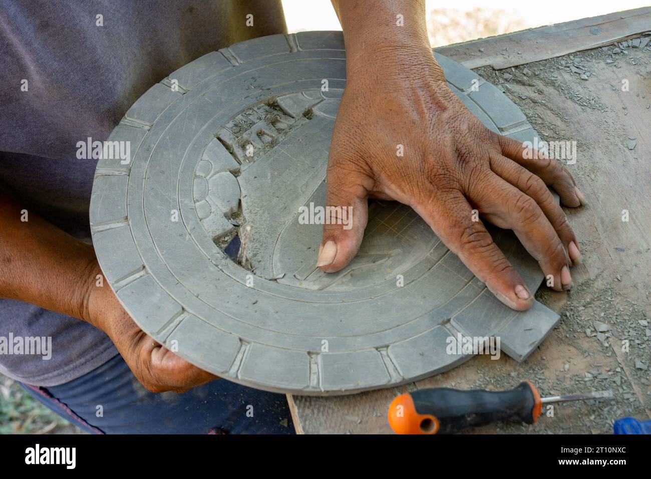 A Mayan craftsman carving a souvenir plaque of a Mayan pyramid on slate ...