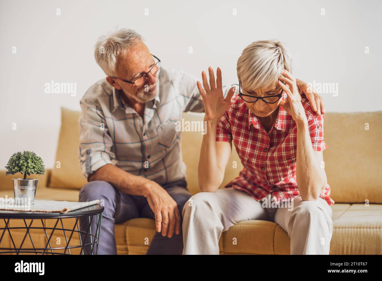 Senior couple sitting in living room and arguing. Woman is angry while ...