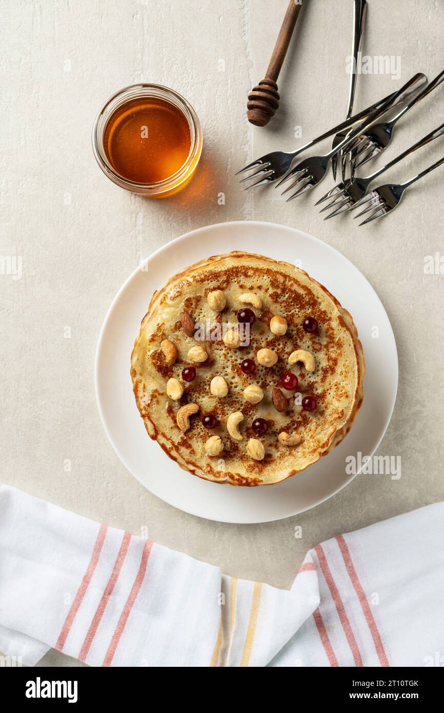 Large pancakes on a light stone background are served by a female cook ...