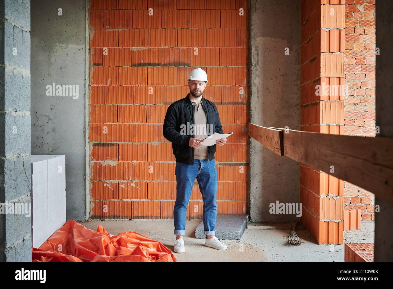 Full length portrait of man worker holding papers and looking at camera ...