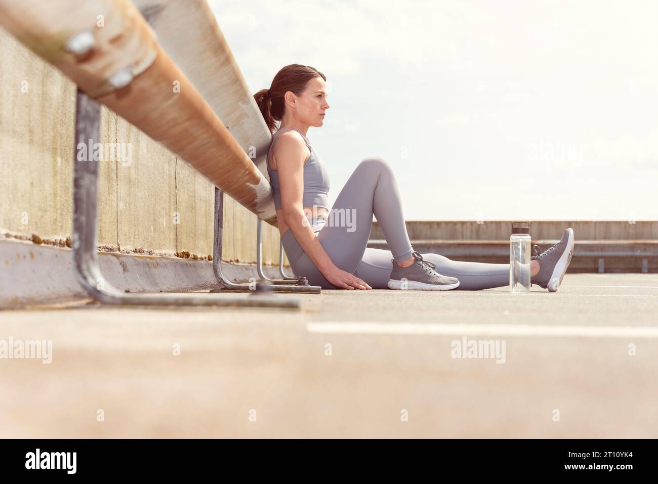 sporty female runner sitting resting after exercise. Urban background ...