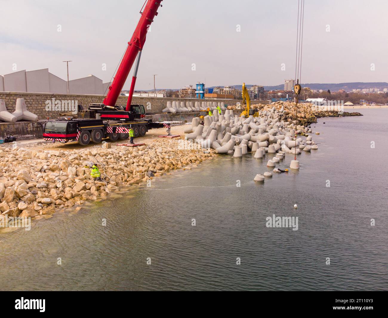 Aerial top view of breakwater construction. Bulldozer and crane on a ...