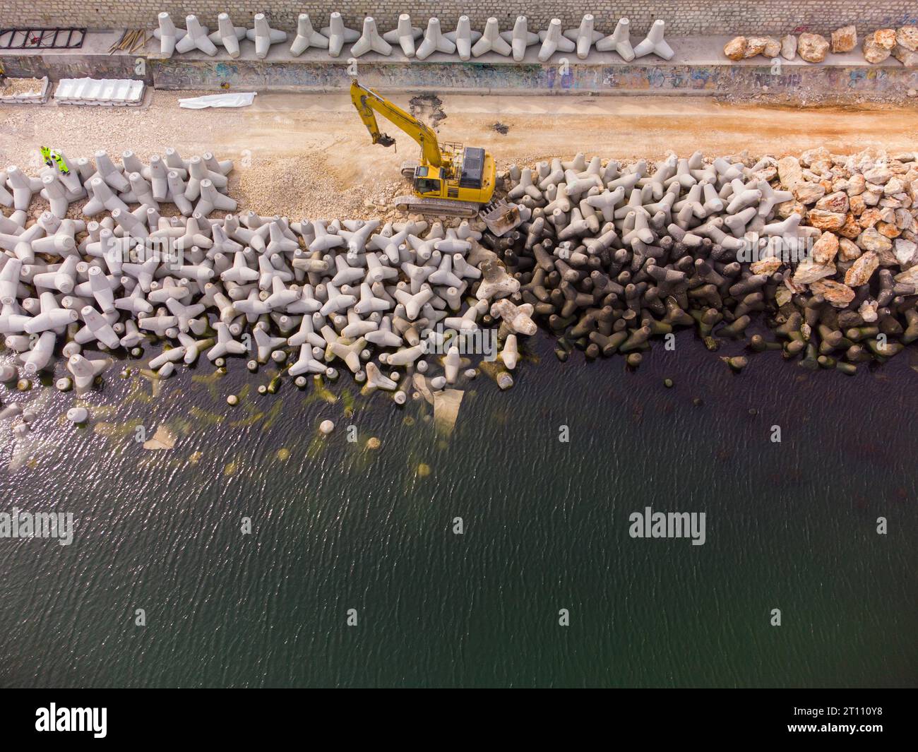 Aerial top view of breakwater construction. Bulldozer and crane on a ...