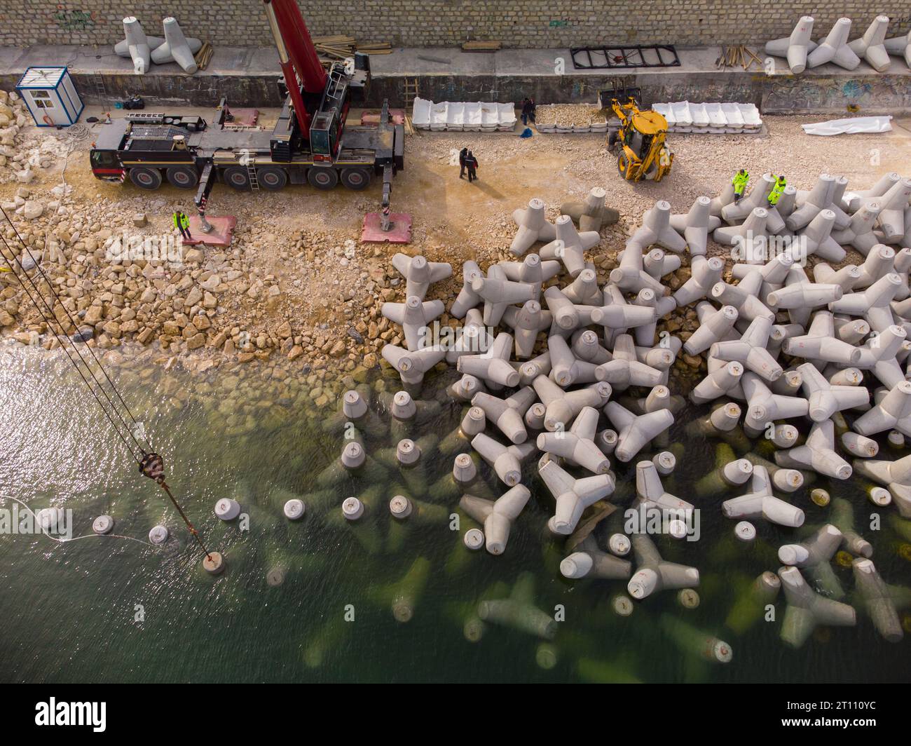 Aerial top view of breakwater construction. Bulldozer and crane on a ...