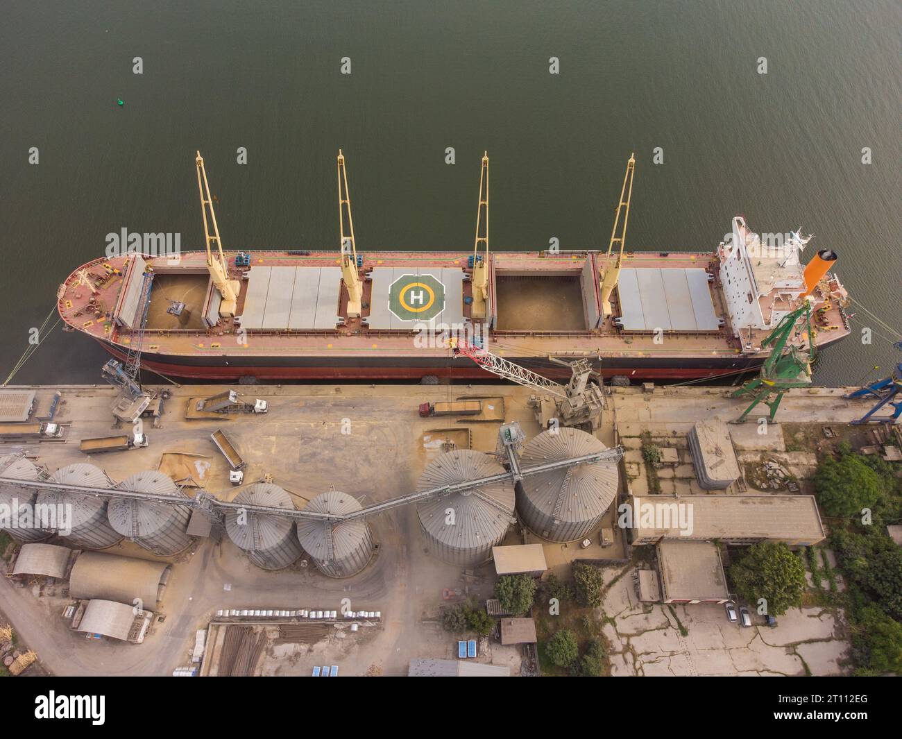 Loading grain into holds of sea cargo vessel in seaport from silos of grain storage. Bunkering ...