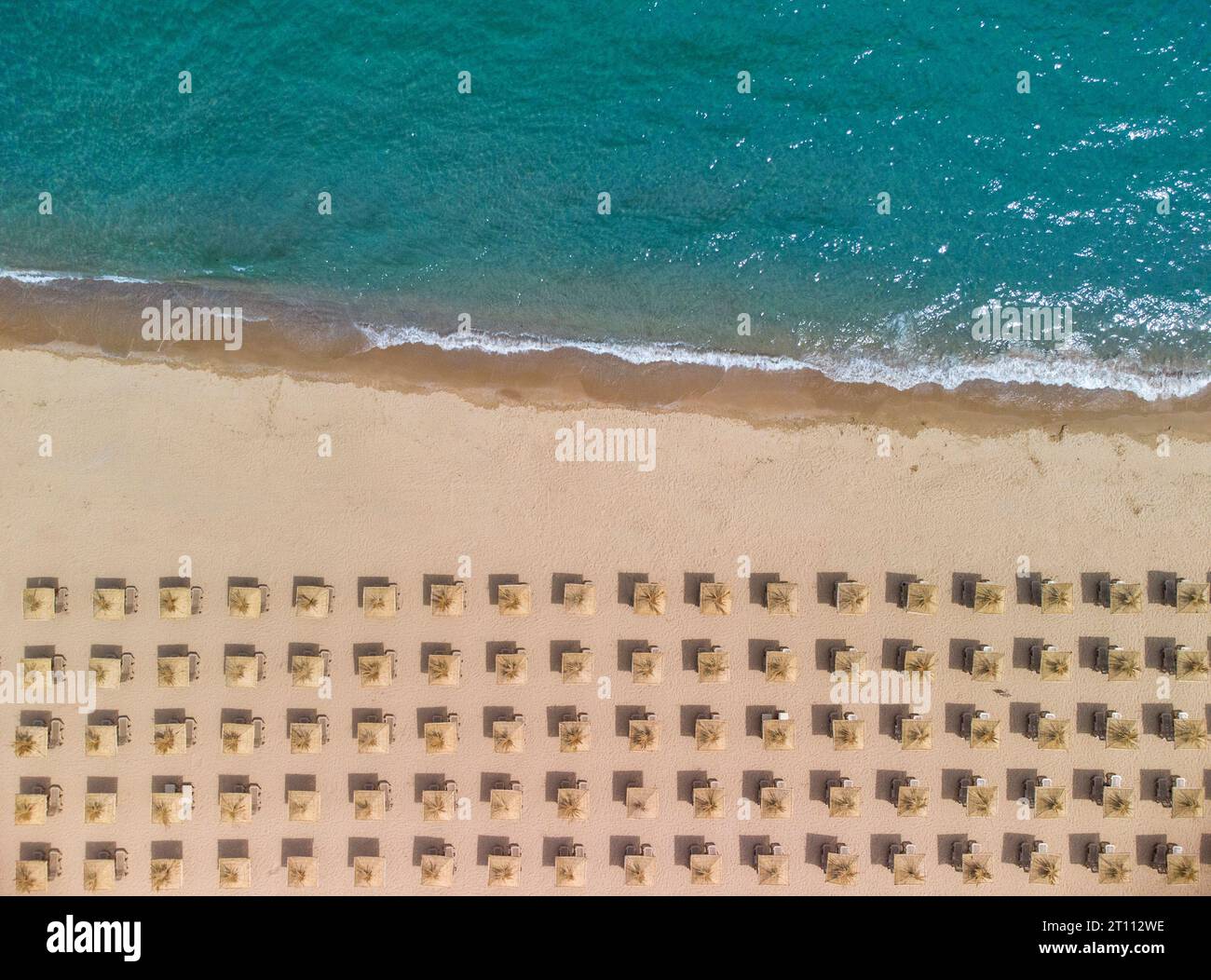 Aerial view of an amazing empty sand beach with straw beach umbrellas ...