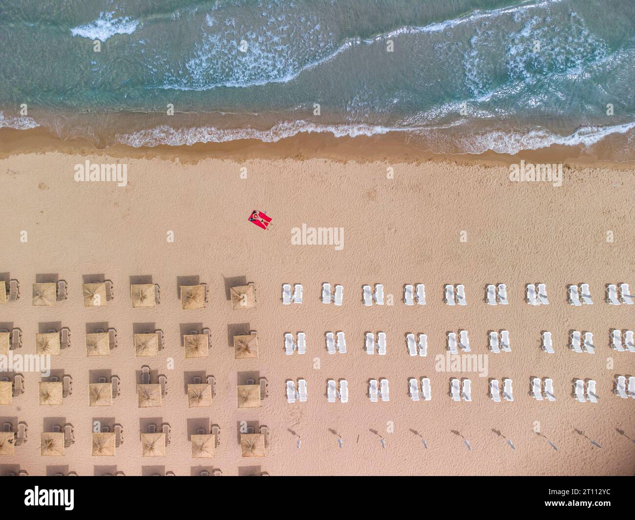 Aerial view of an amazing empty sand beach with straw beach umbrellas ...