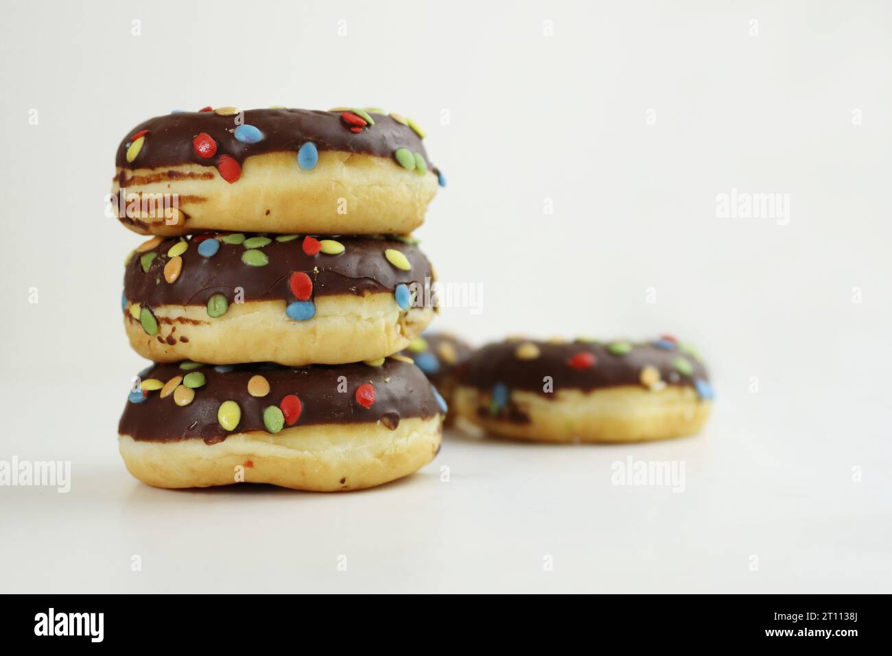 A stack of doughnuts glazed with chocolate and colorful smarties. Pile ...