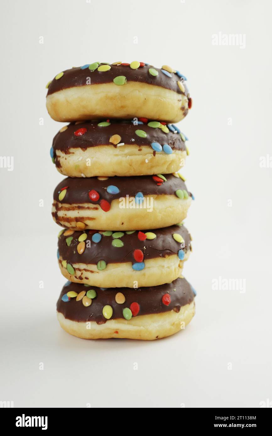 A stack of doughnuts glazed with chocolate and colorful smarties. Pile ...