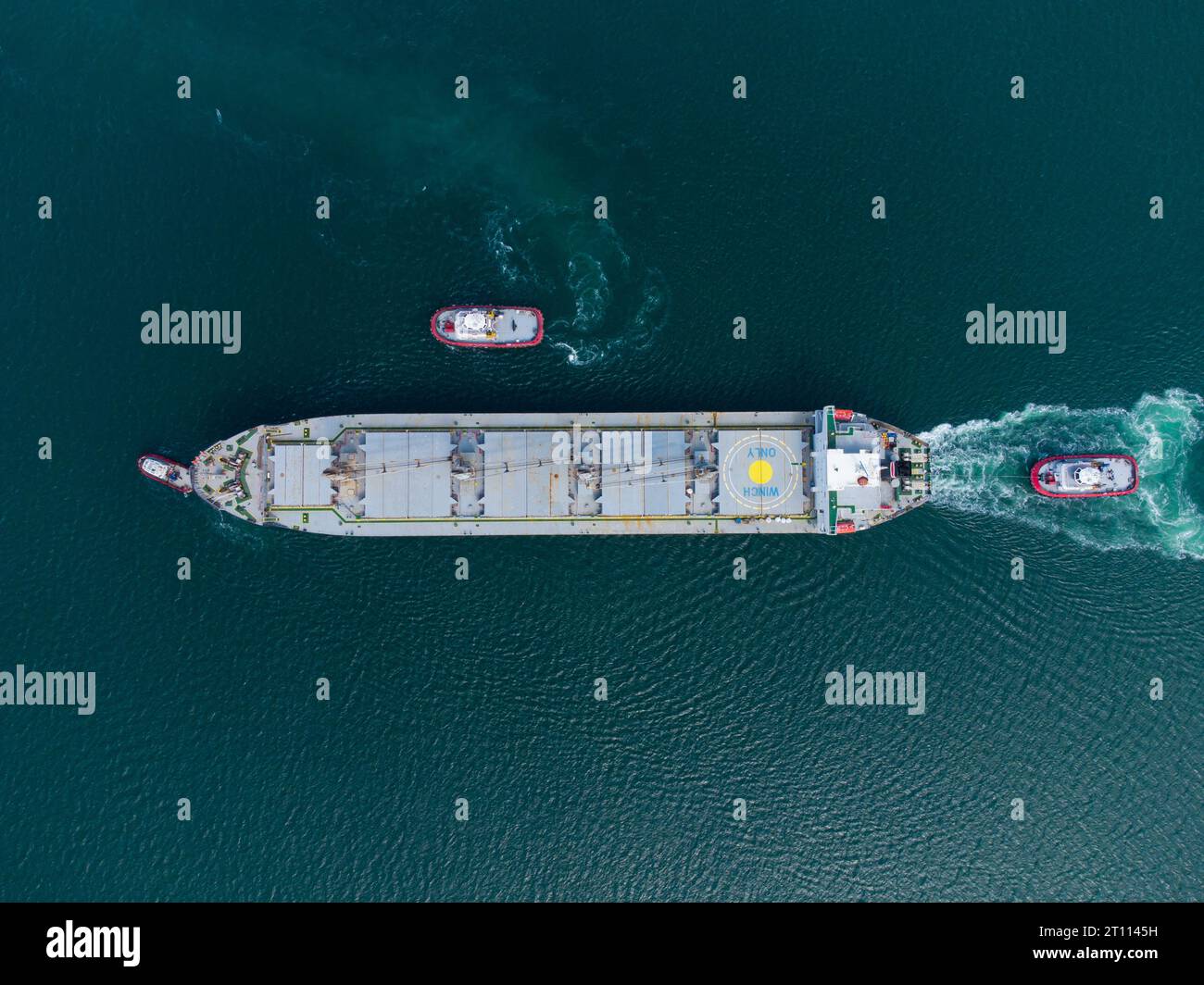 Aerial top view of tug boat assisting big bulk carrier cargo ship ...