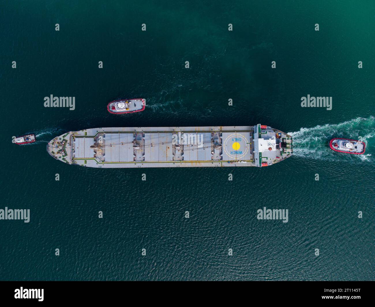 Aerial top view of tug boat assisting big bulk carrier cargo ship ...