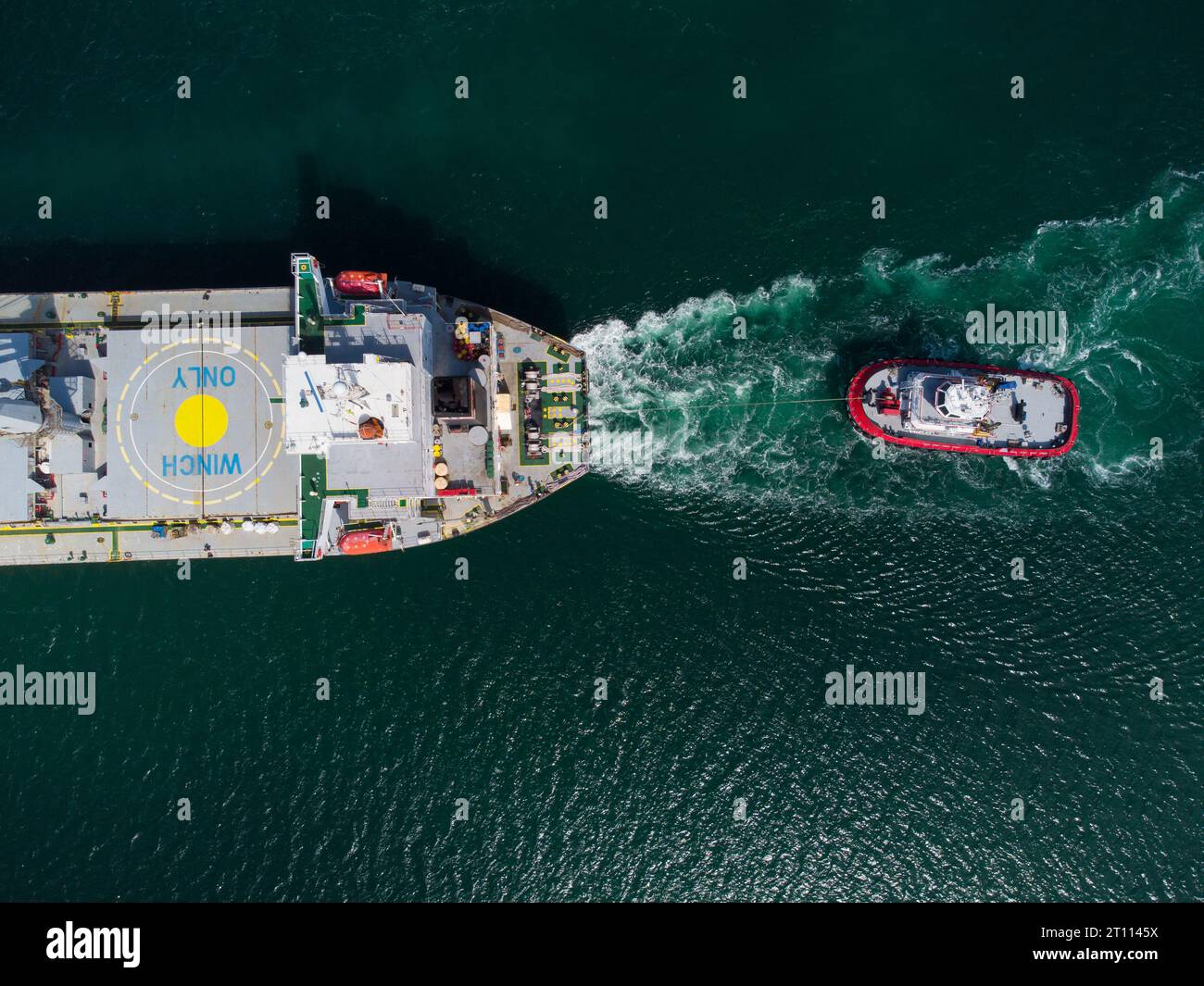 Aerial top view of tug boat assisting big bulk carrier cargo ship ...