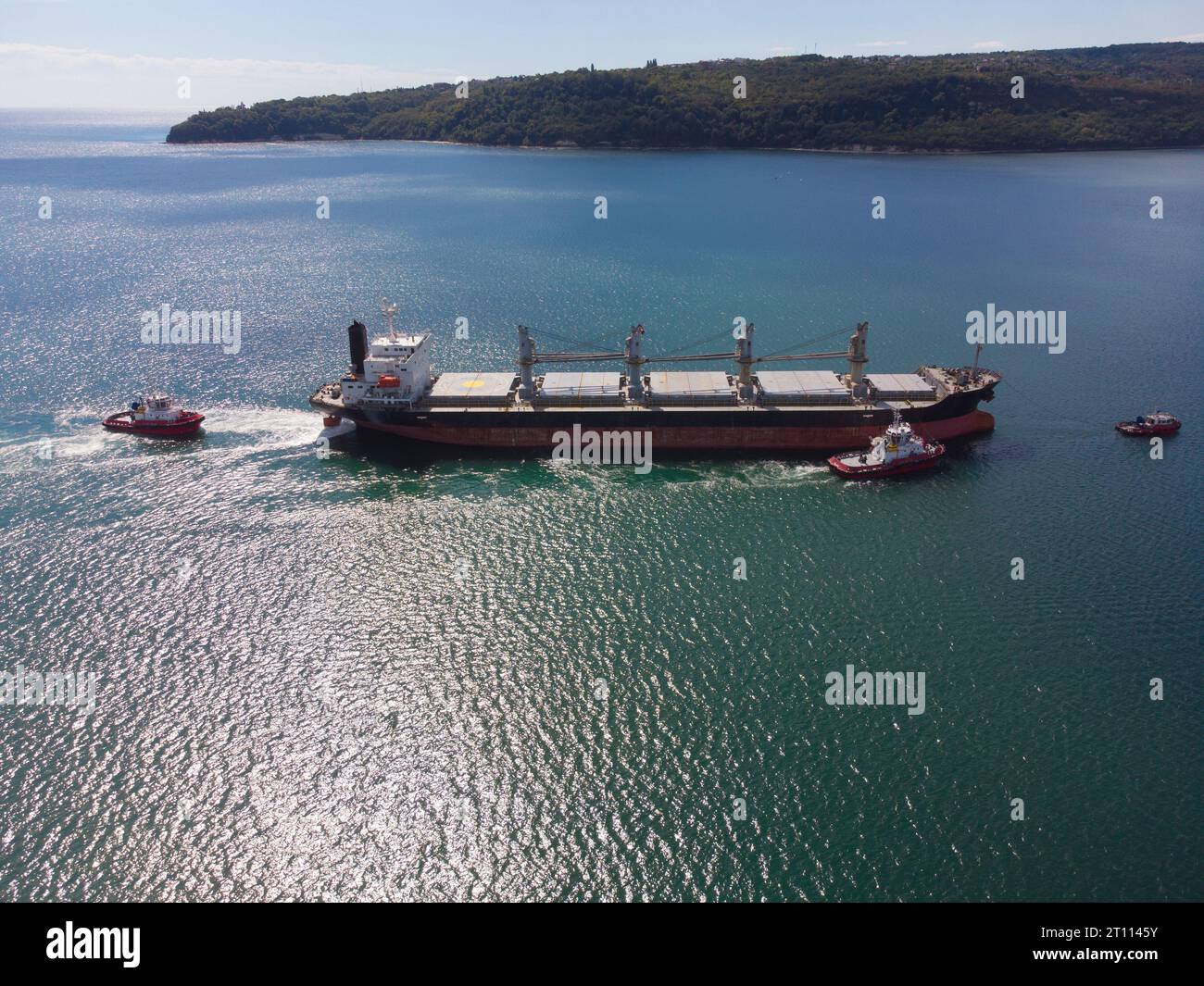 Aerial top view of tug boat assisting big bulk carrier cargo ship ...