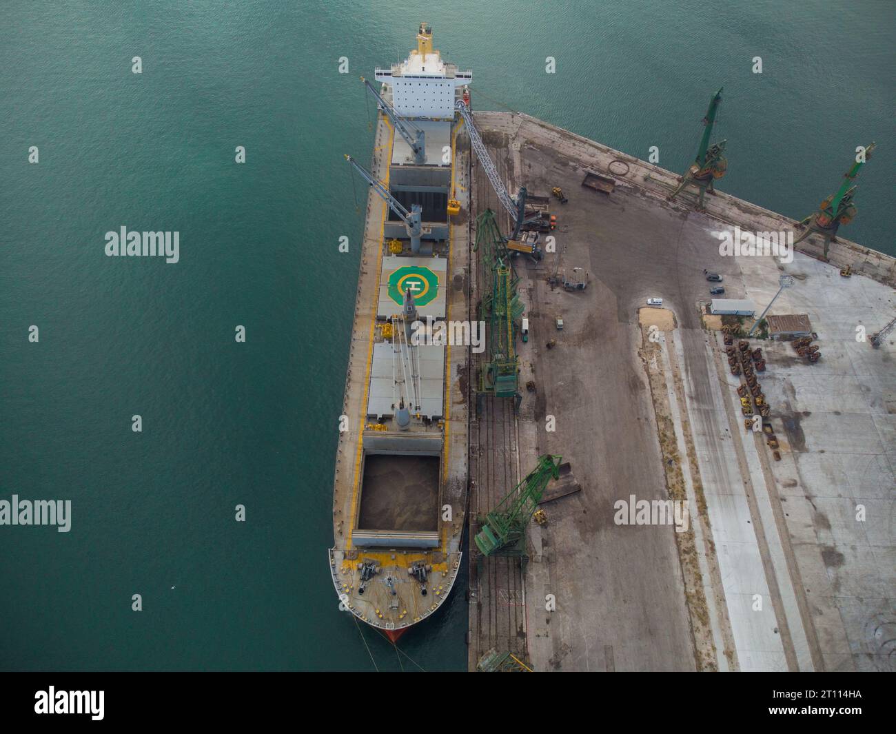 Aerial top view of big cargo ship bulk carrier is loaded with coal in ...