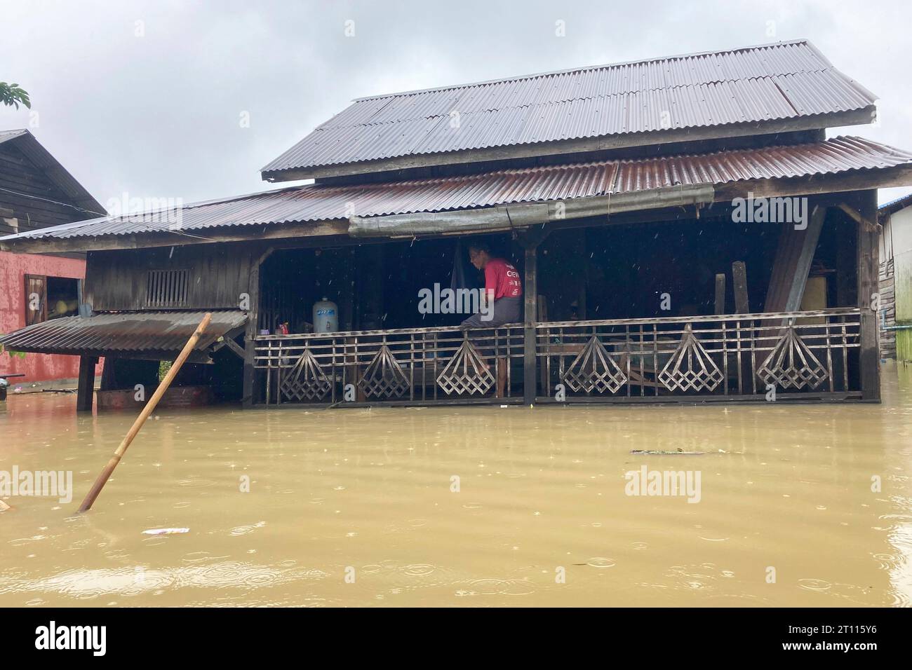 A man sits at their half-submerged house in Bago, about 80 kilometers ...