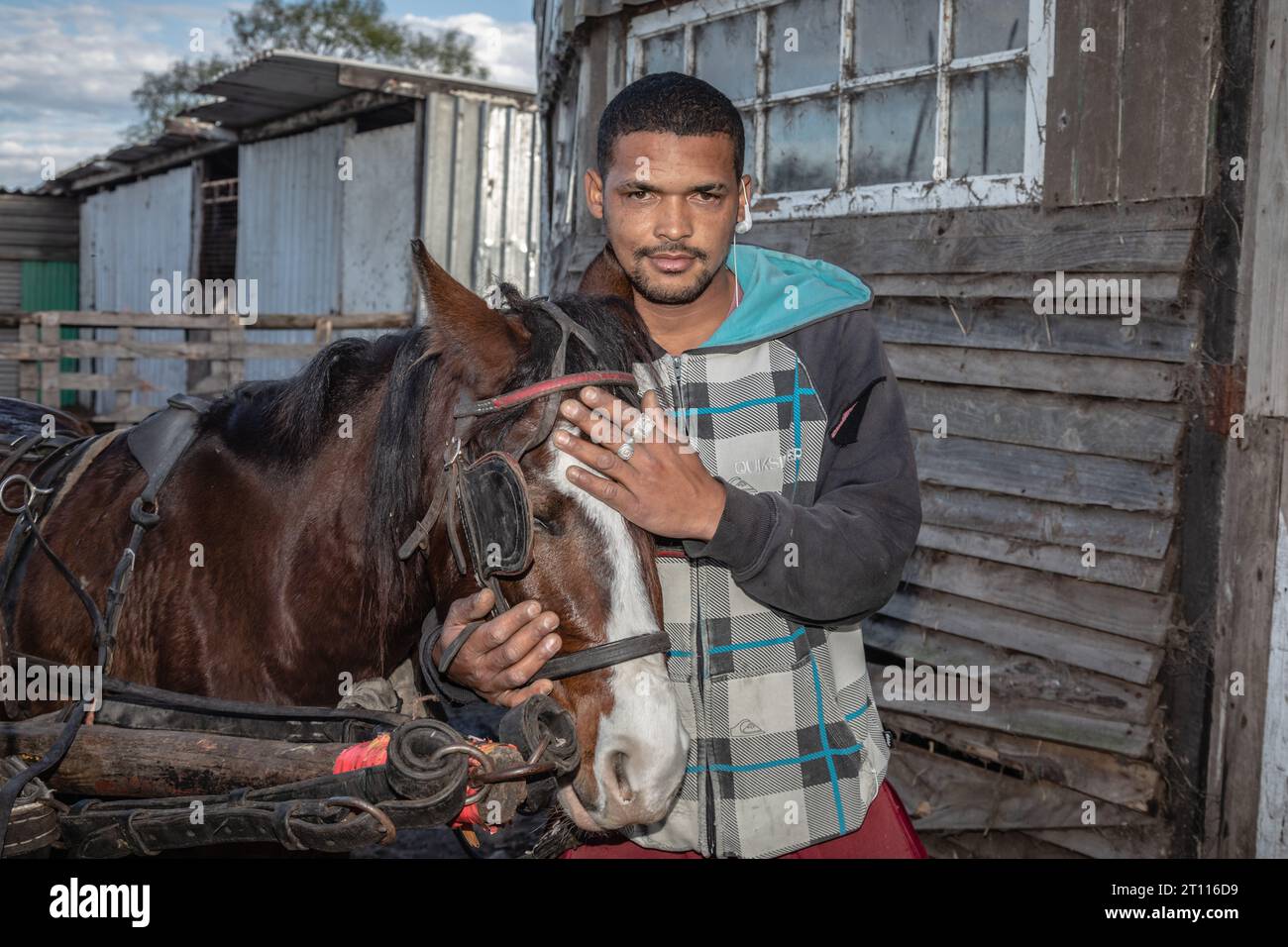 Amidst weathered structures, a impoverished mixed-race man, dressed in ...