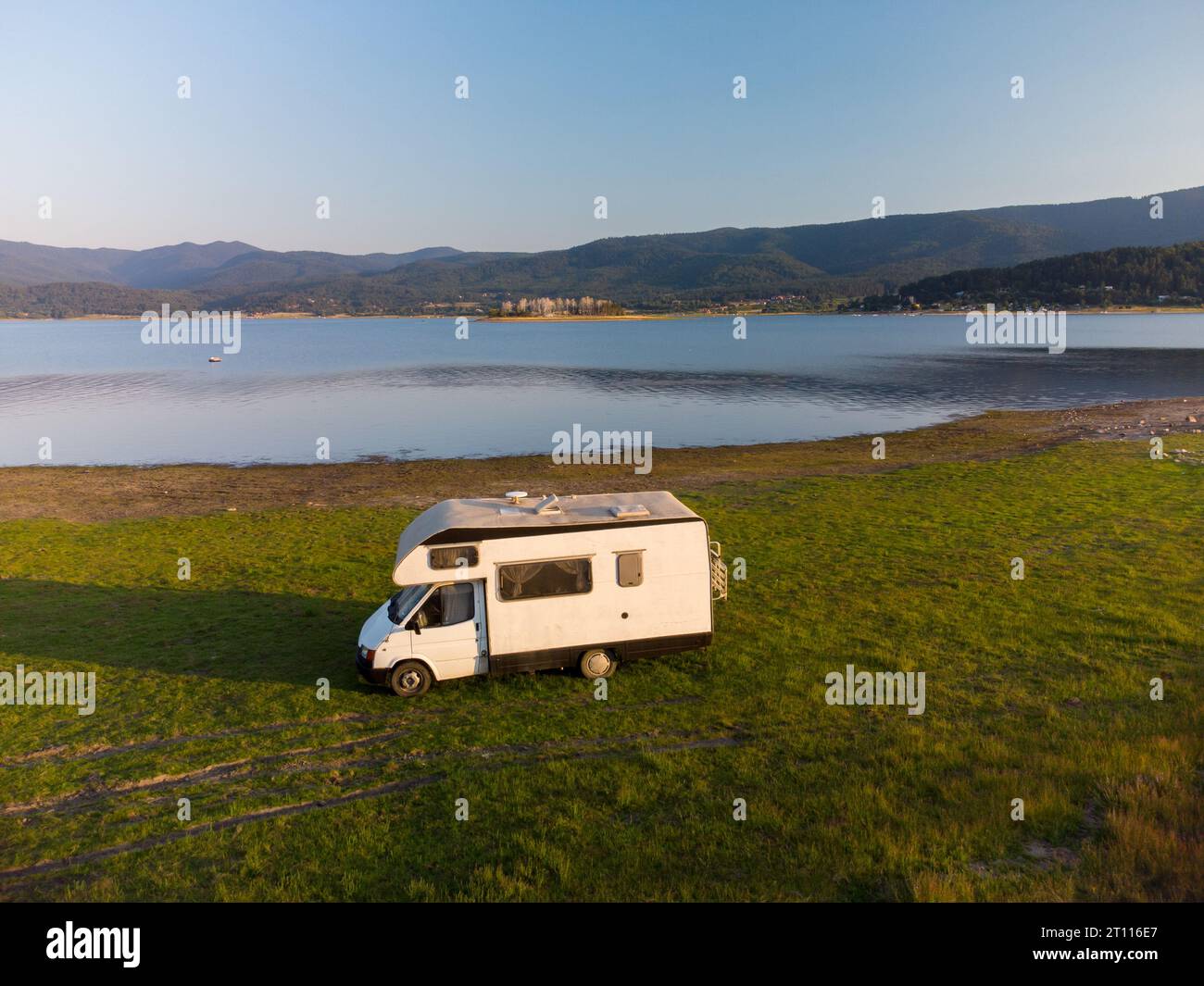 Aerial top view of a camper van parked on a beach, mountain range ...