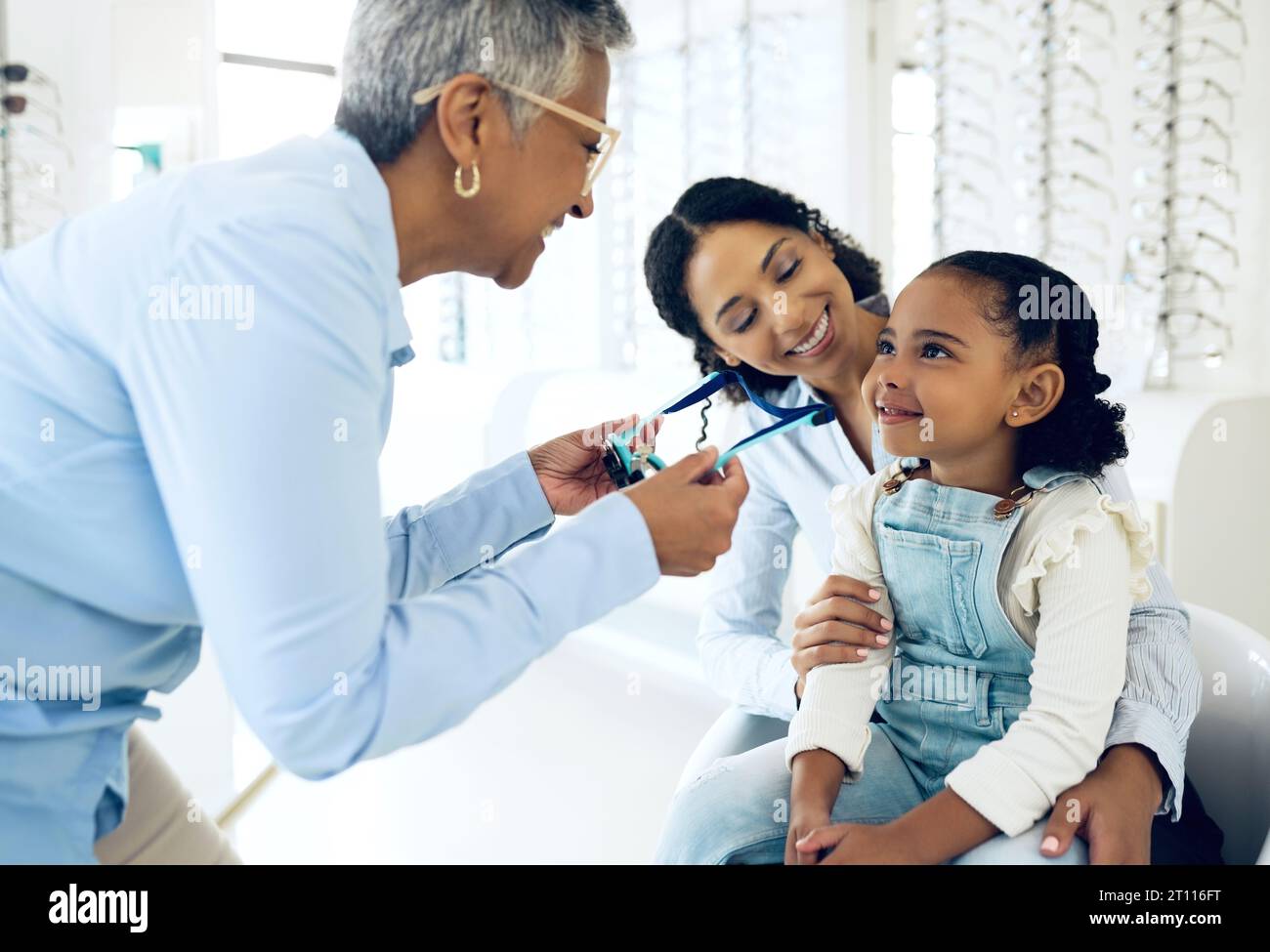 Optical, glasses and optometrist with child and mother at an eye care ...