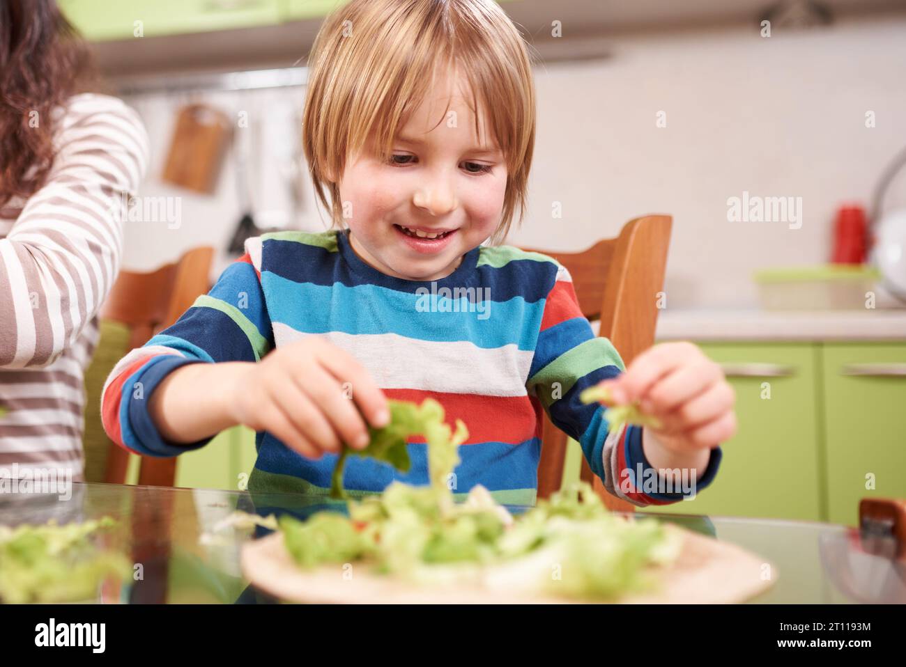 An adorable 4 year old preschool boy cooking fresh vegetable salad in ...