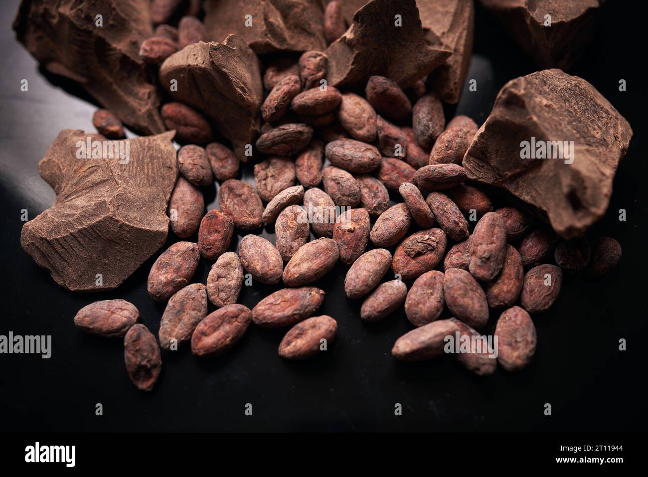 Cocoa beans and chocolate pieces on dark background, close up Stock ...