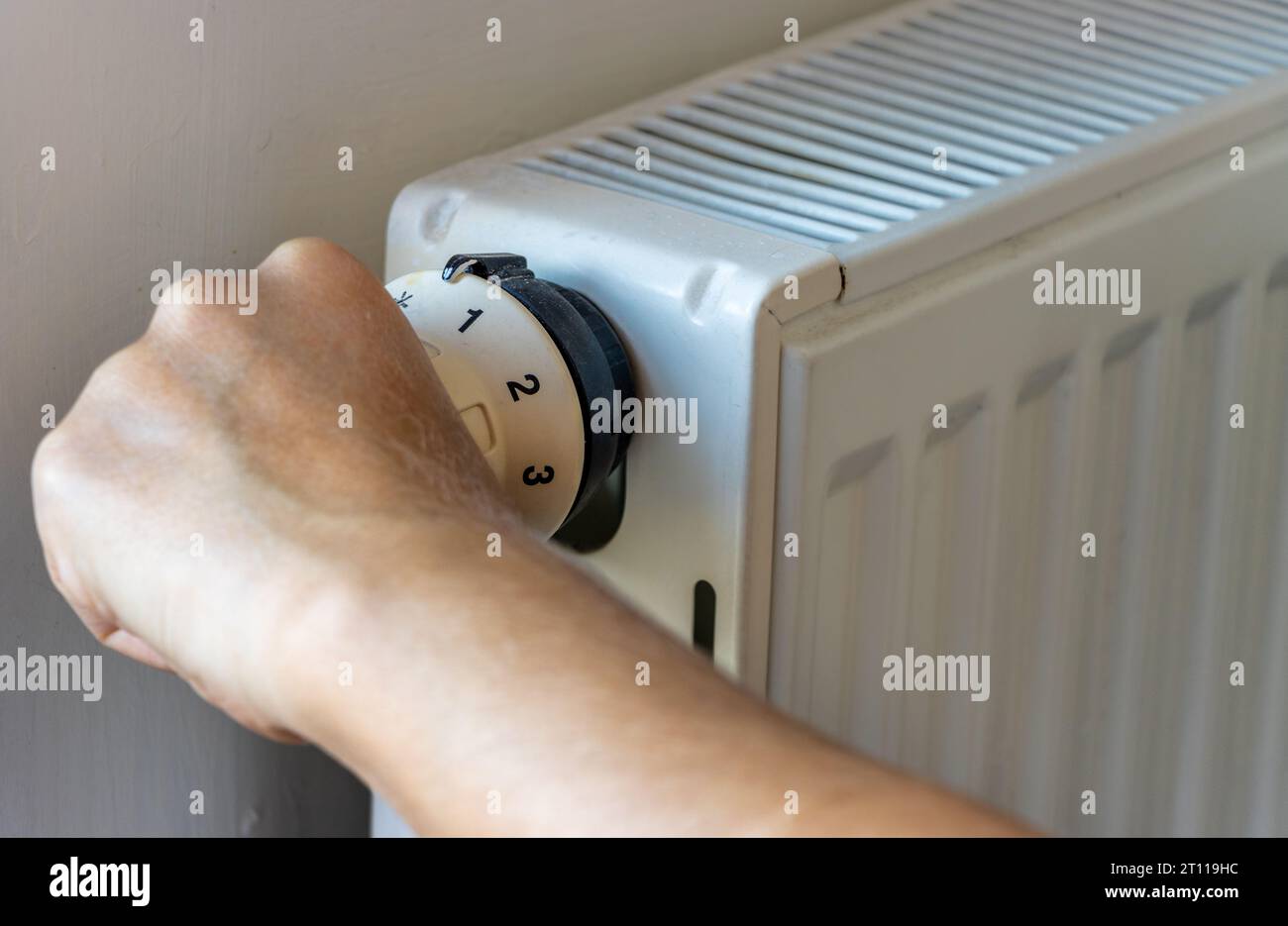 Woman adjusts the valve of the heating radiator at home. Energy, fuel ...