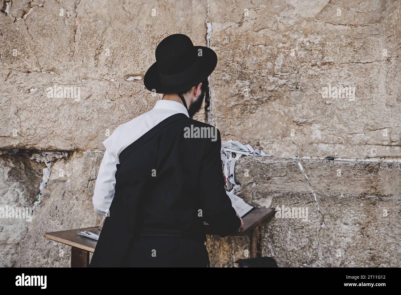 Young religious jew standing against the Wailing Wall with holy book ...