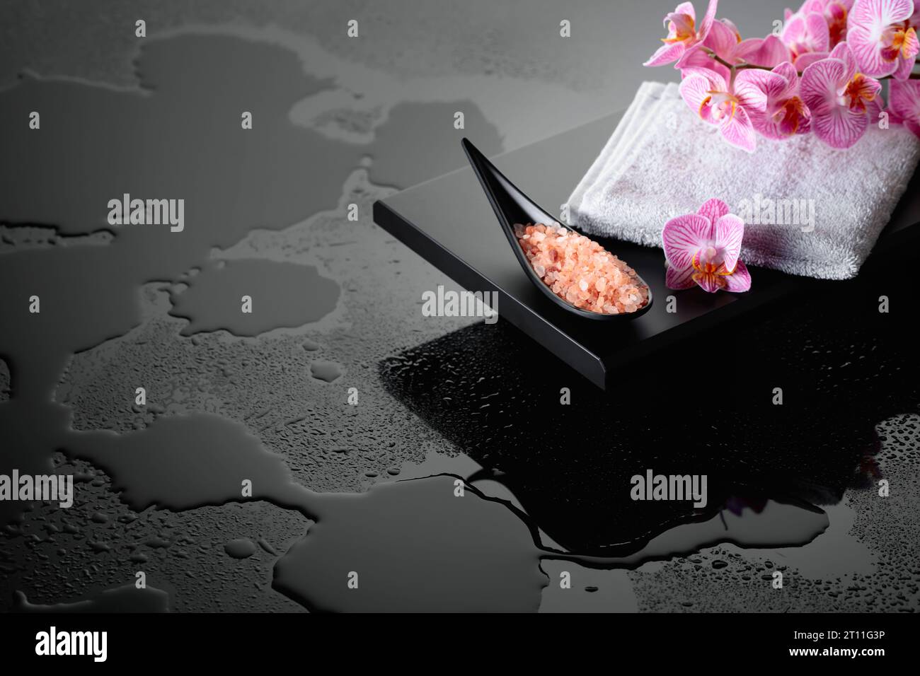 Beautiful blooming orchid flowers and pink sea salt. Black reflective ...