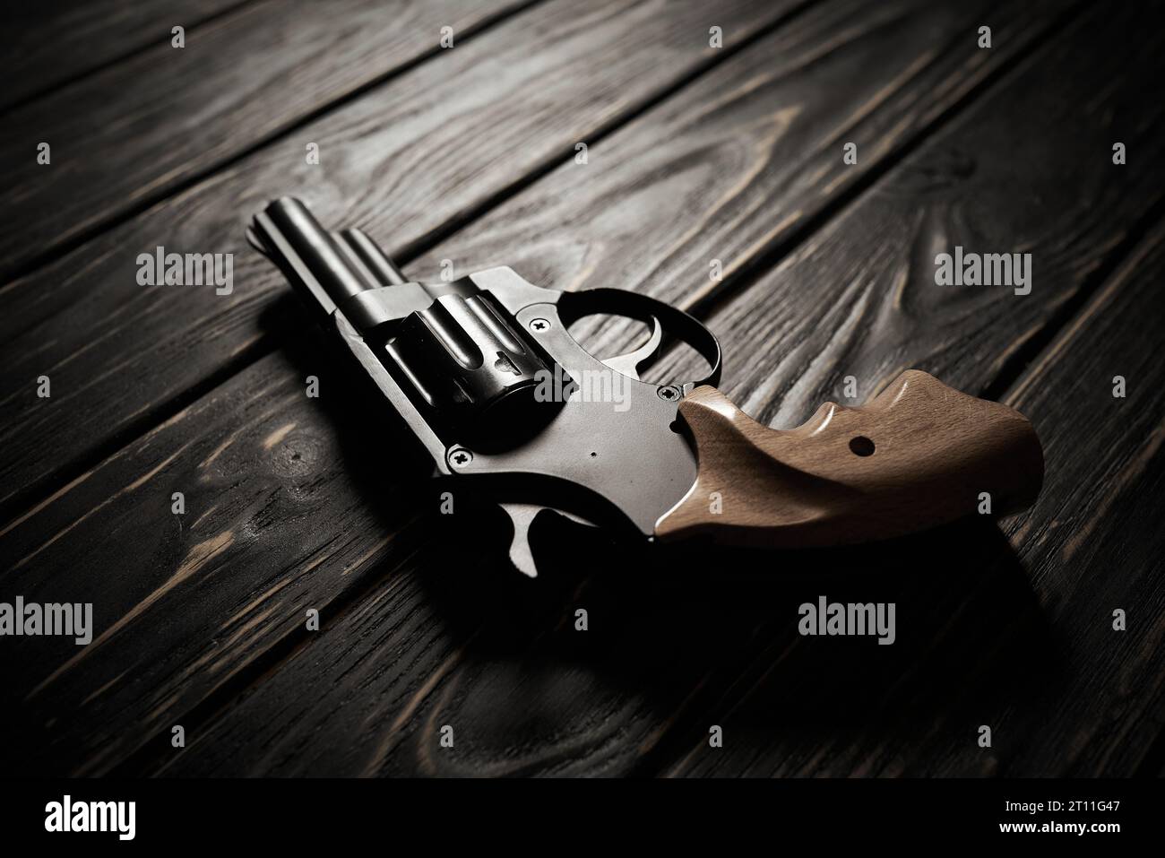 Black revolver pistol on dark wooden background Stock Photo - Alamy