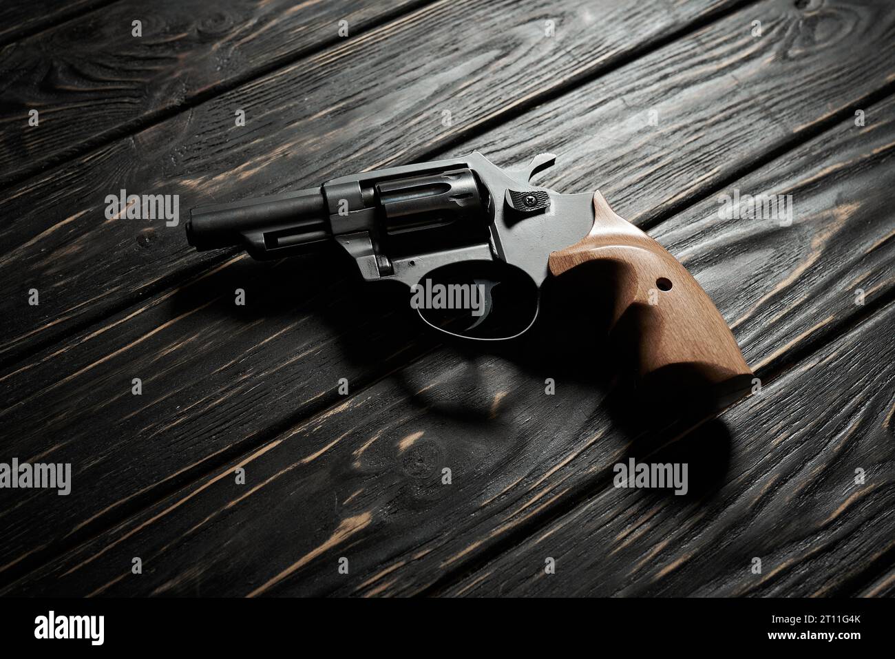 Black revolver pistol on dark wooden background Stock Photo - Alamy
