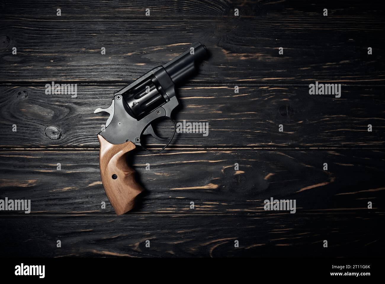 Black revolver pistol on dark wooden background Stock Photo - Alamy