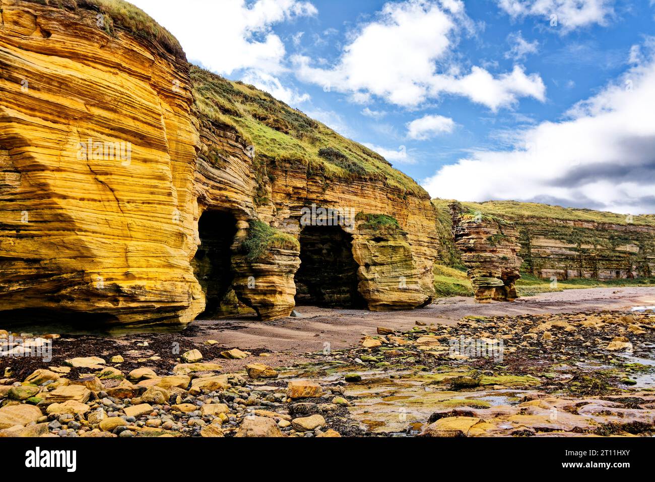Hopeman Moray Coast Scotland two dark cave entrances to golden coloured ...