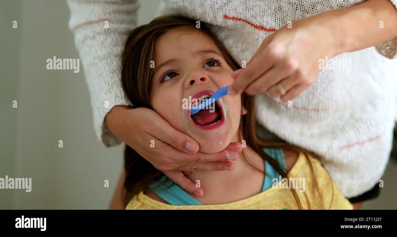 Parent brushing daughter teeth before bed. Mother brushes little girl ...