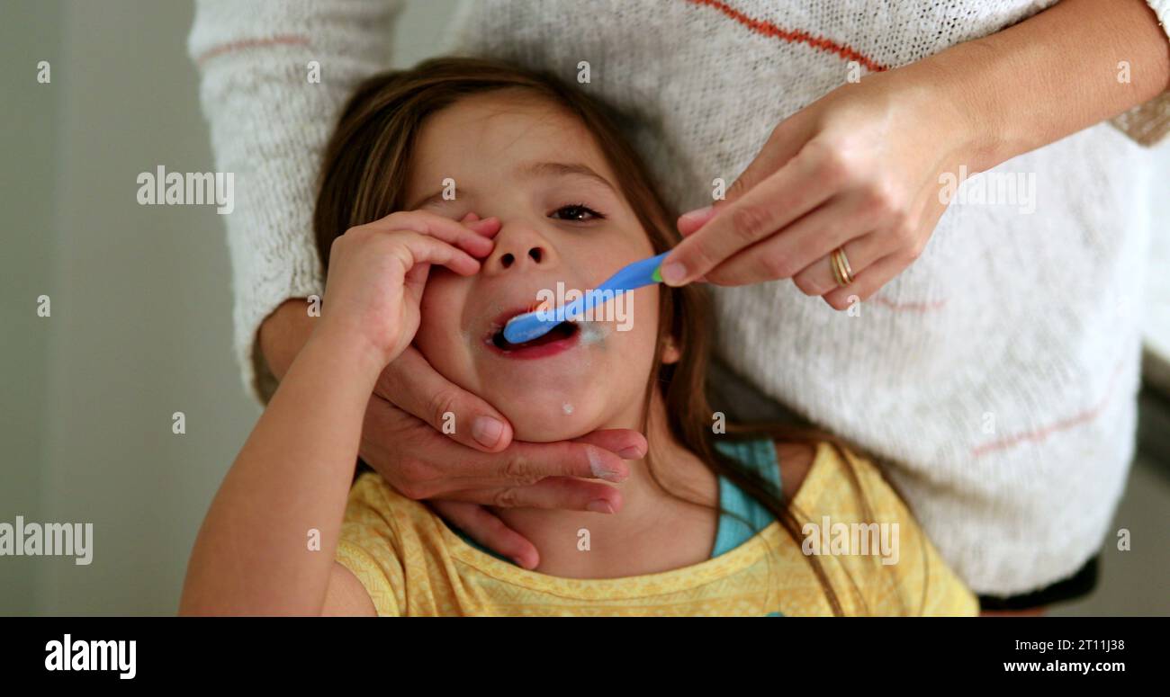 Parent brushing daughter teeth before bed. Mother brushes little girl ...