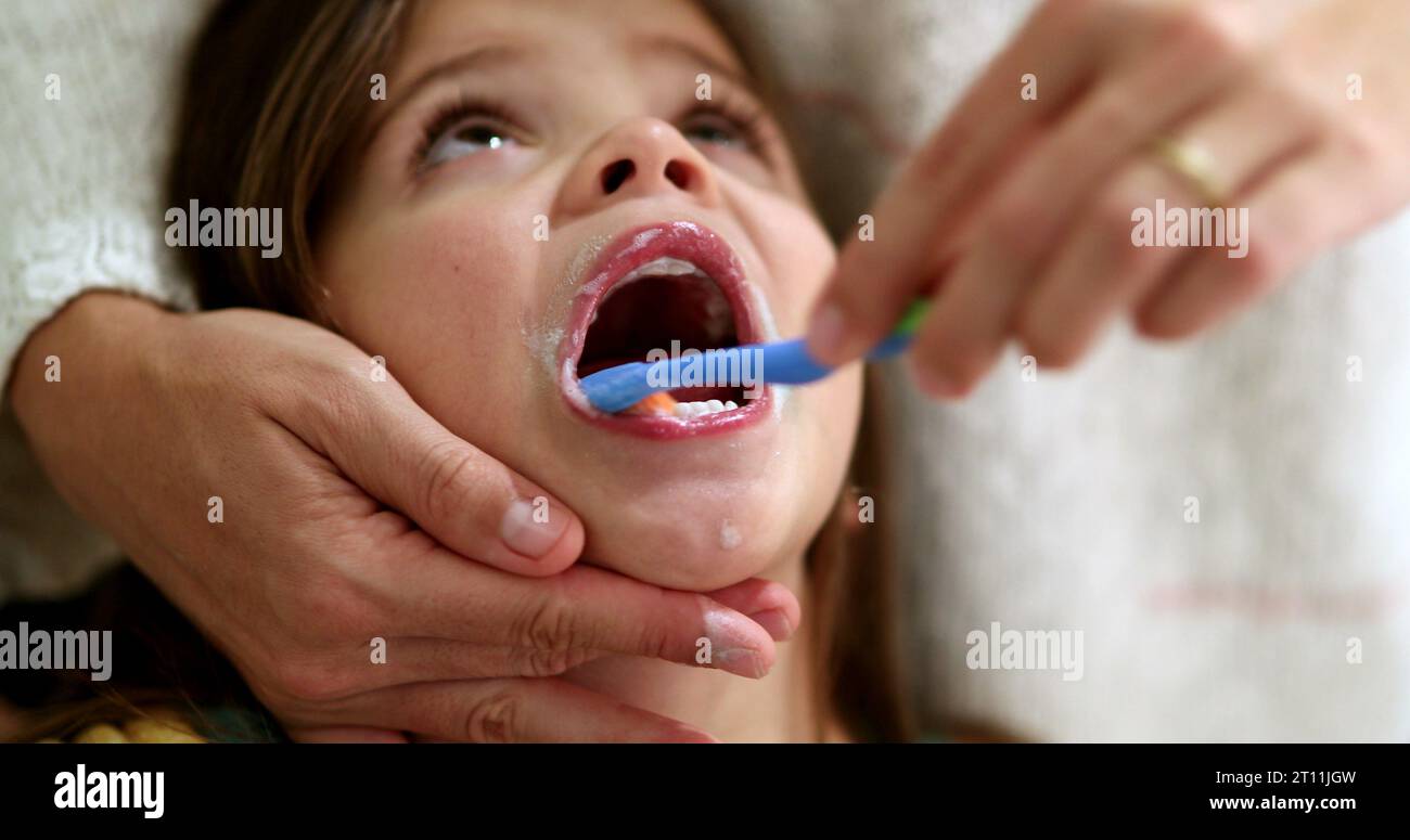 Mother brushing child teeth. Parent brushes daughter tooth with ...
