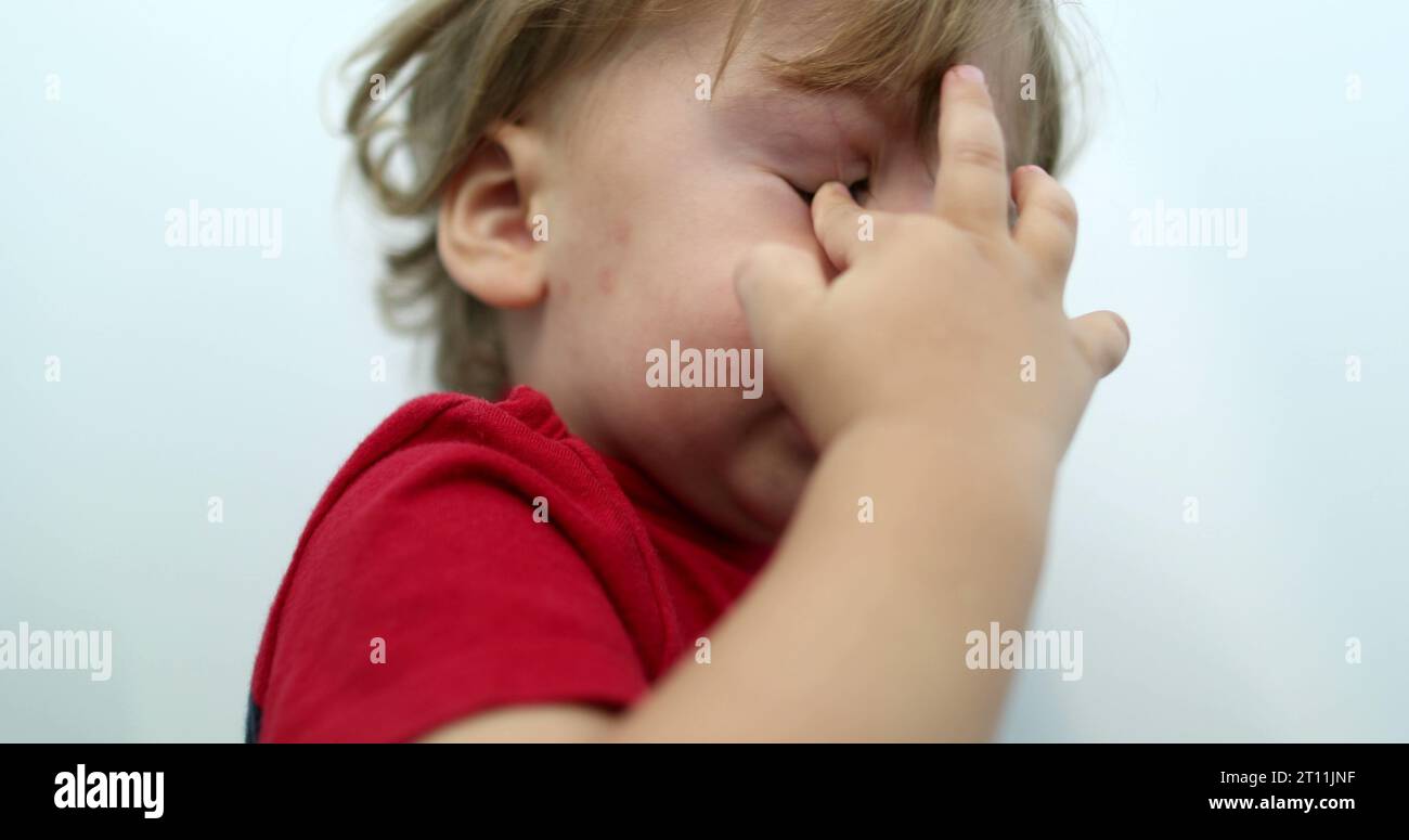 Tired toddler boy rubbing eye with hand. Sleepy baby child Stock Photo ...