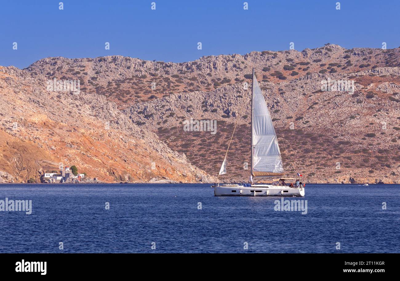 White pleasure yacht in the bay of Symi island on a bright sunny day ...