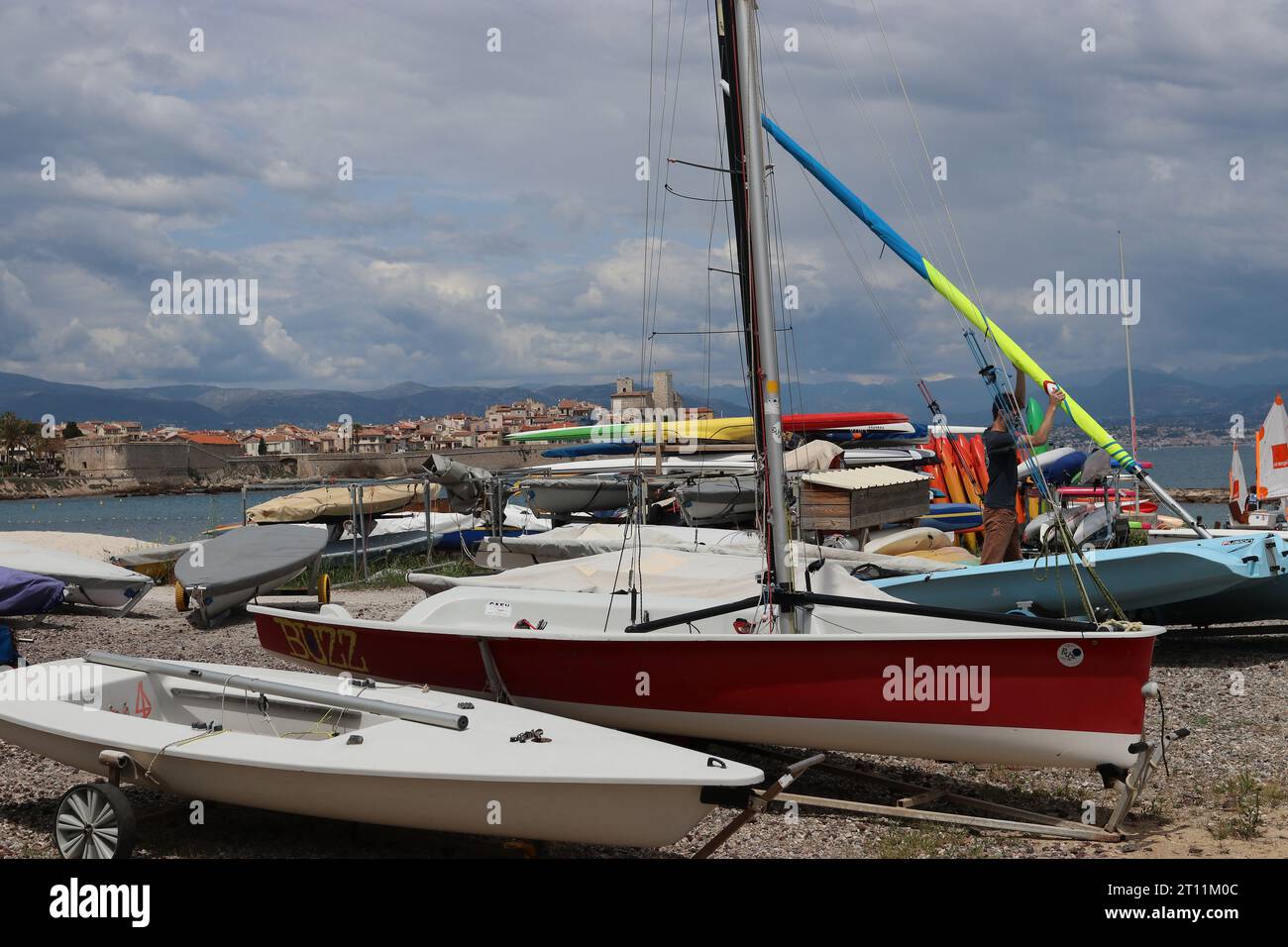 Buzz sailing dinghy and a variety of sailing skiffs sit on the beach at ...