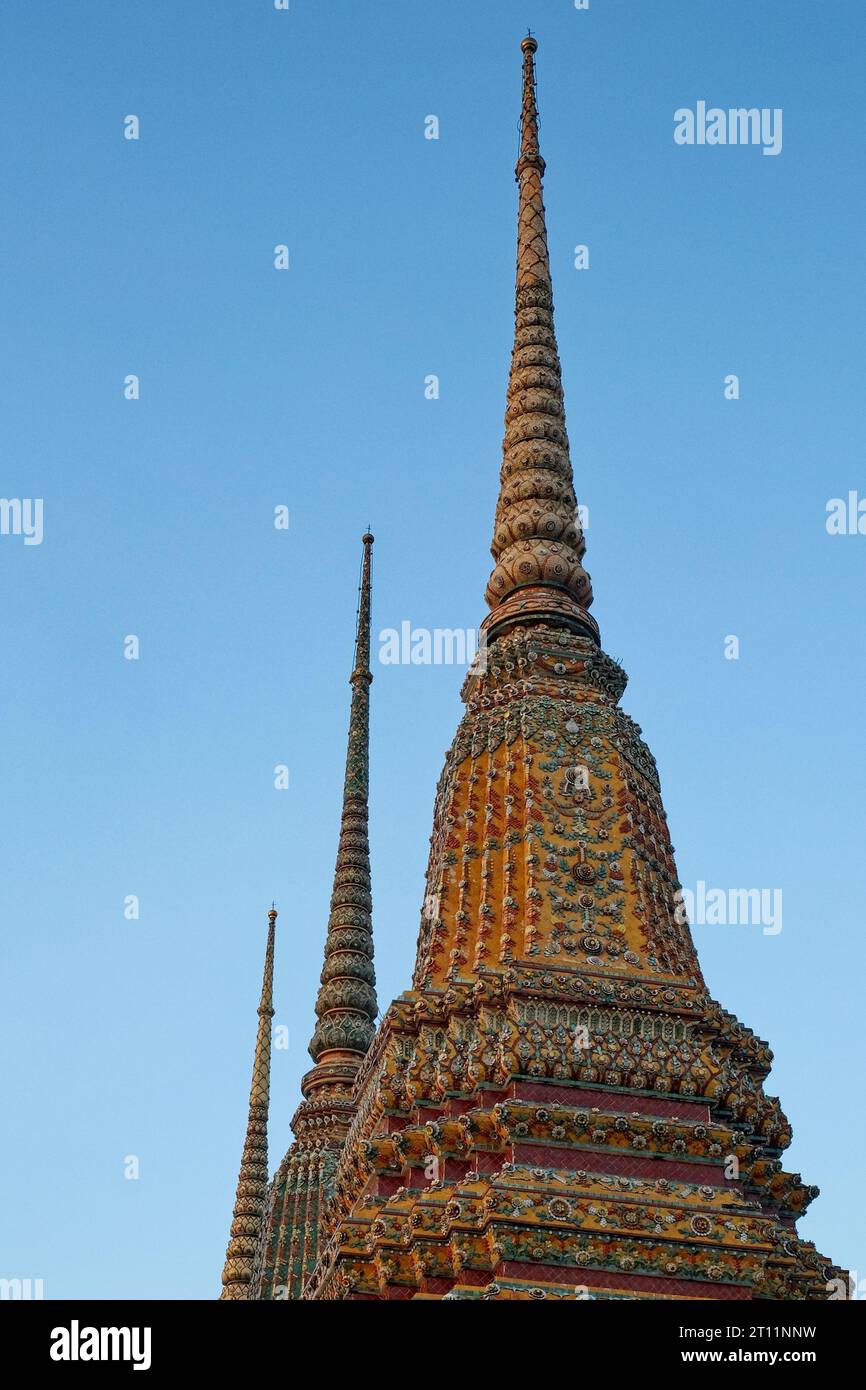 Three ornate temple spires against a blue sky. The spires are decorated ...