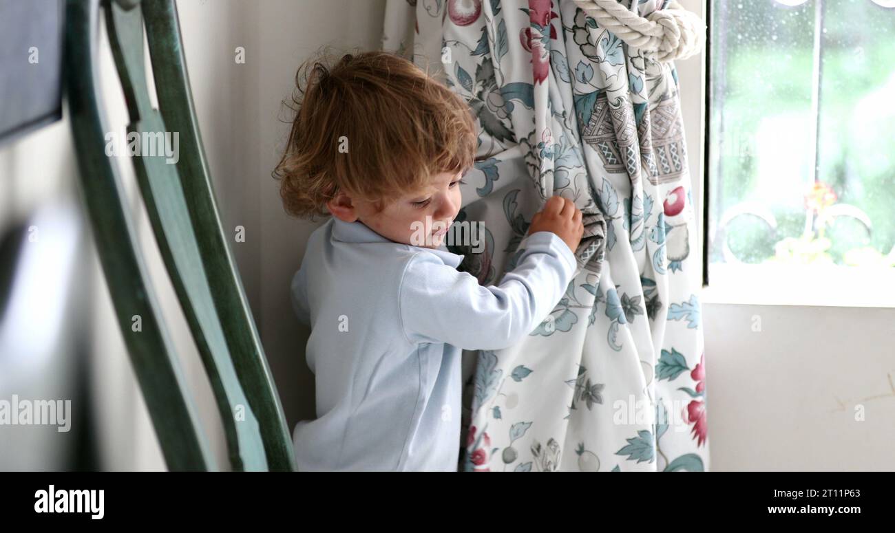 Cute toddler boy hiding behind curtain Stock Photo - Alamy