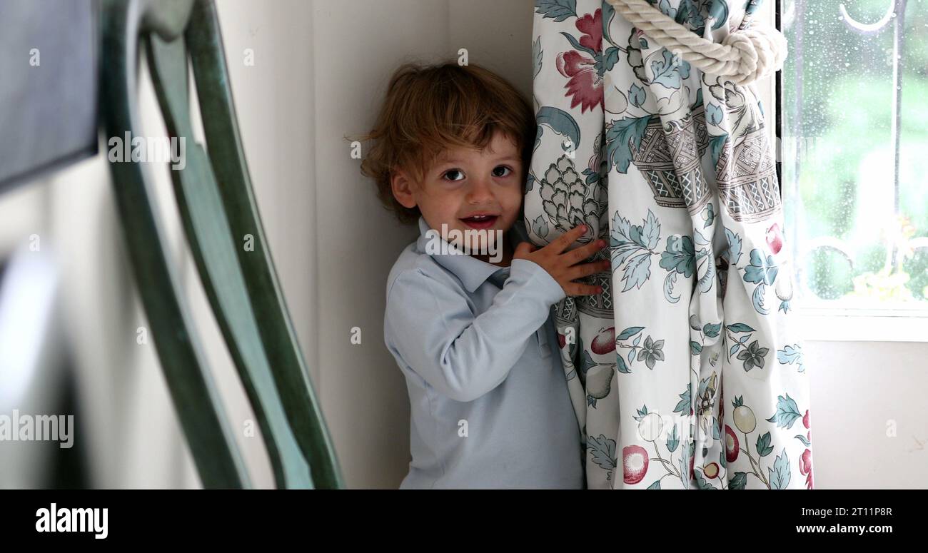 Cute toddler boy hiding behind curtain Stock Photo - Alamy