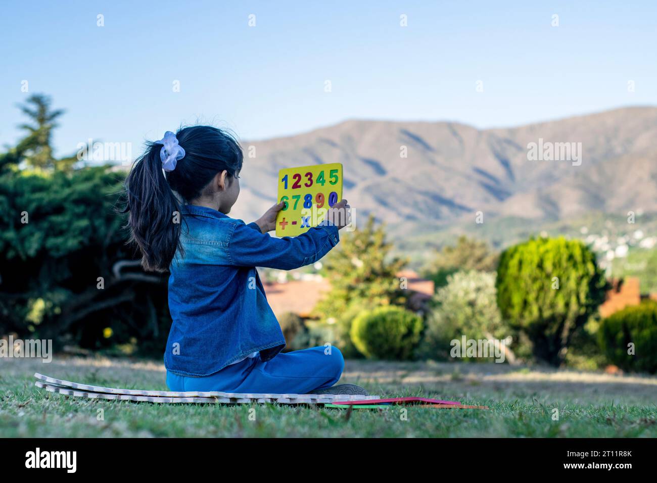 Little girl watching a board with colorful numbers in a park full of ...