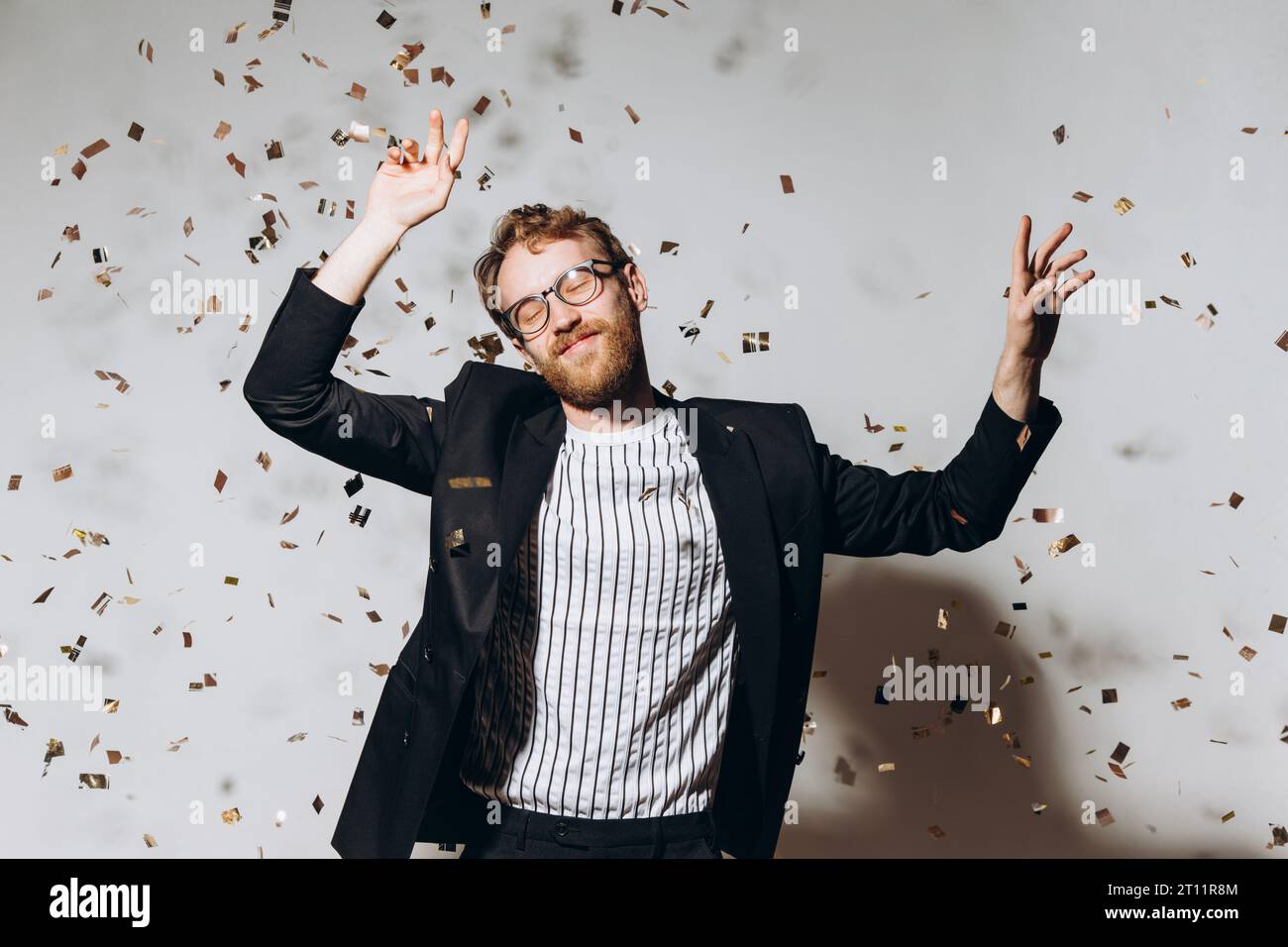 Celebration time. Portrait of a happy guy dancing under glittering ...